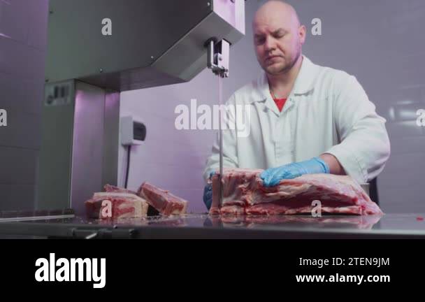 Industrial processing of meat. A man cook cuts a piece of tenderloin in ...
