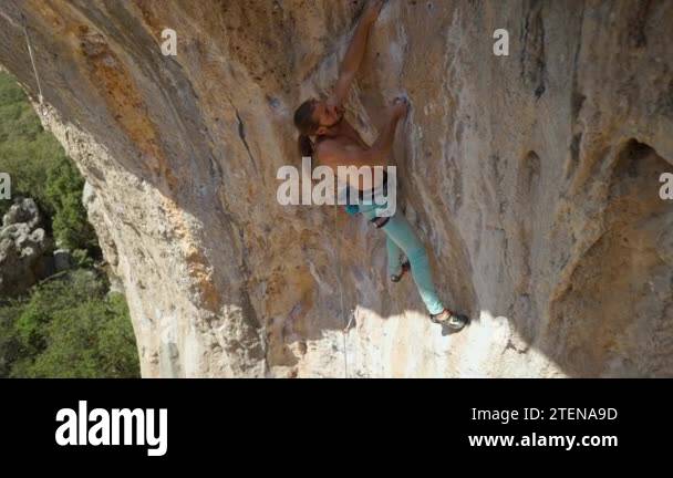 young powerful athletic man rock climber with long hair climbing on ...