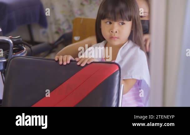 Asian little girl gets her hair cut at a beauty salon by a hairdresser. Hairdresser makes ...