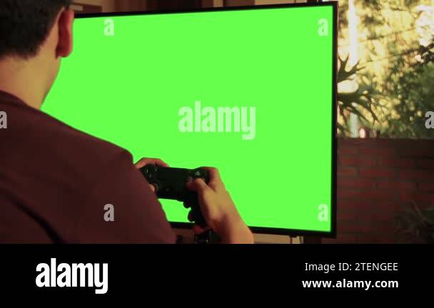Gamer playing on a TV with Green Screen. You can replace green screen ...