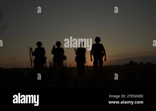 Two armed men with weapon walking across field after combat operation ...