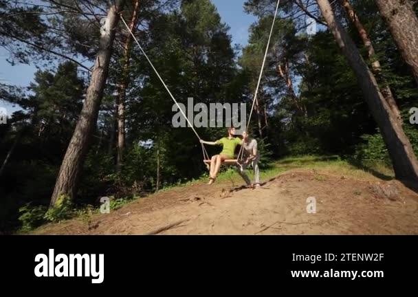 An attractive teenager on a high swing. The happy girl soars high in ...