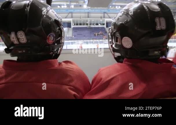 children hockey players in black helmets and red uniforms sit on the ...