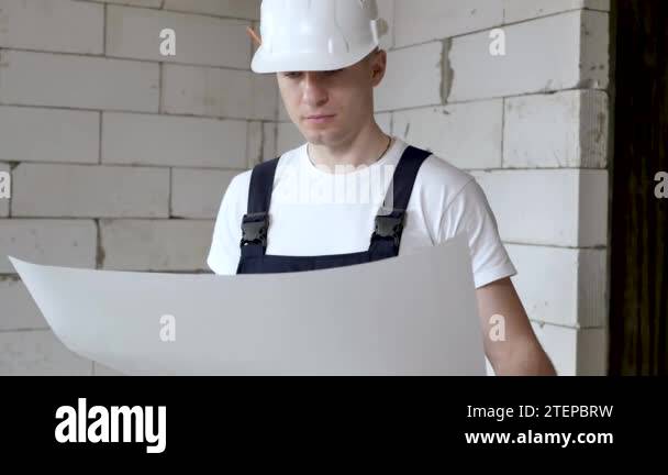 Portrait of an architect-builder studying the layout plan of the ...