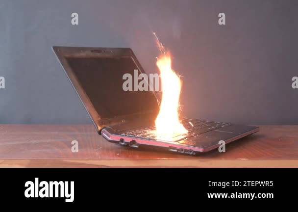 In the room on the table, a laptop caught fire, flames and sparks, a ...
