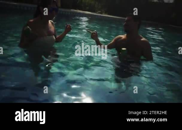 two friends floating their beer cans in the pool at a country house in ...