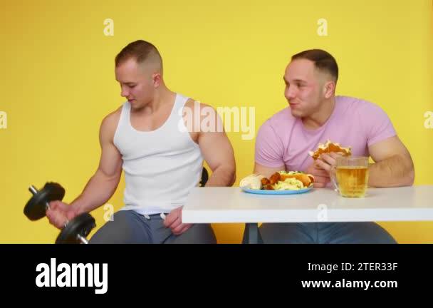 Two muscular twins on a yellow background. One guy swings with ...