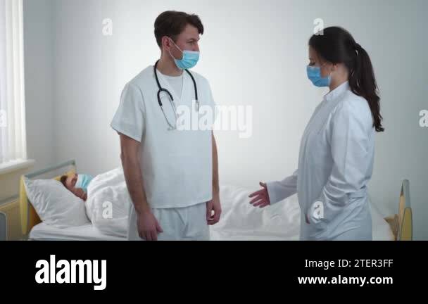 Intelligent Caucasian doctors shaking hands standing in hospital ward ...