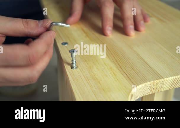 Close-up hands assembling wooden furniture. Man putting together planks ...