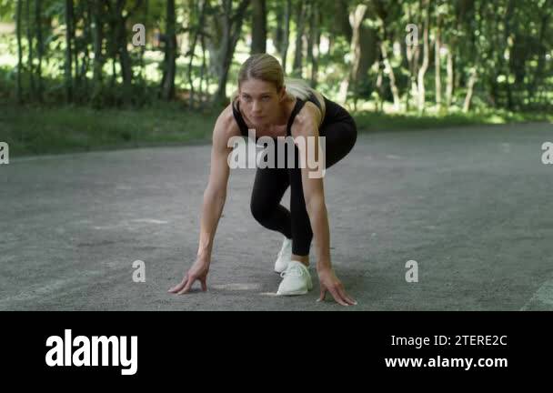 Ready, steady, go. Sporty middle aged woman runner standing in start ...