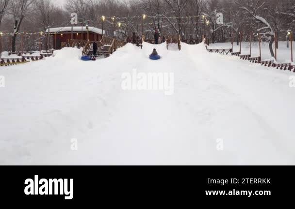 Mom and daughter riding down a snow slide on a hovercraft. Ice slides ...