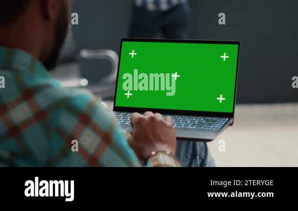 Male patient using greenscreen display on laptop computer, sitting in ...