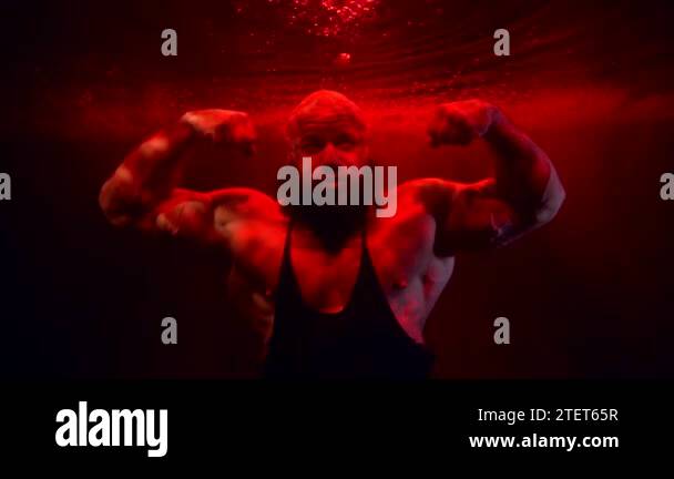 muscular sportsman is showing his huge biceps, floating underwater ...