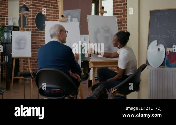 Woman explaining to senior man how to draw model on canvas Stock Video ...