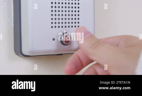 Person presses a doorbell, hanging on white wall, or an intercom call ...
