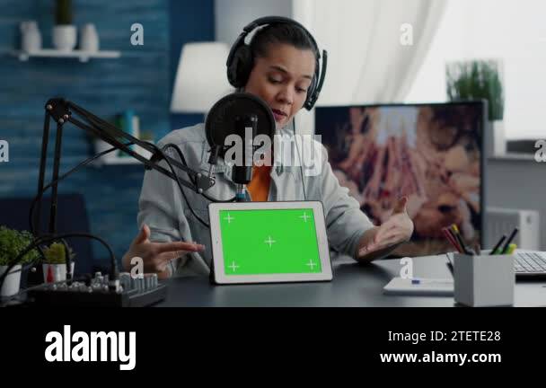 Influencer in studio promoting product on tablet with green screen ...