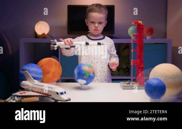 Little blonde boy kid plays with spaceship from constructor, flies near ...