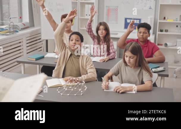 Medium slowmo of multiethnic smart middle school pupils raising their ...