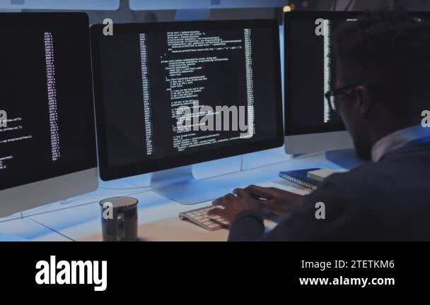 Over shoulder of young Black male programmer sitting at desk in ...