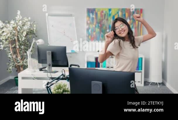 Happy satisfied office worker got promotion she dances between desks in ...