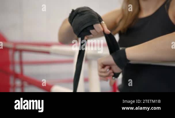 A girl with blond hair gathered in a bundle wraps her hand in boxing ...