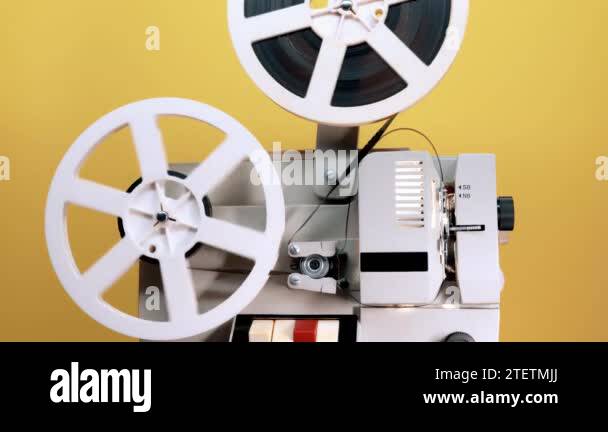 Retro reel with film rotating on yellow studio background. Old ...