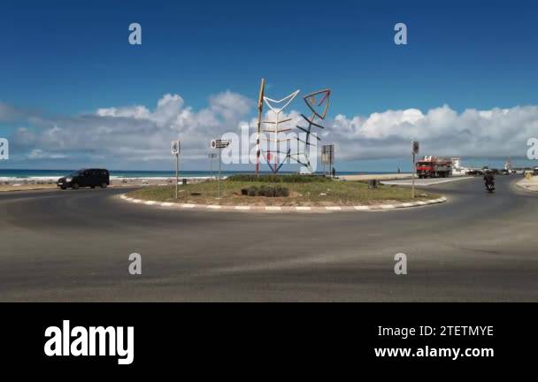 Cars driving around a metallic fish statue roundabout in Assilah Stock ...
