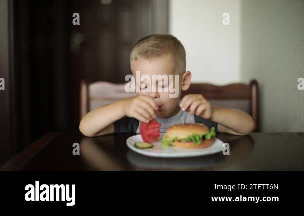 Little boy in fast food cafe eats burger. little kid eating burger ...