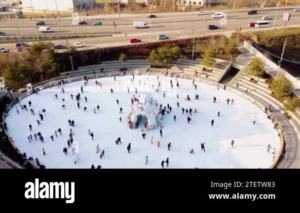 City ice skating rink in open air and road bridge in city. Aerial drone ...