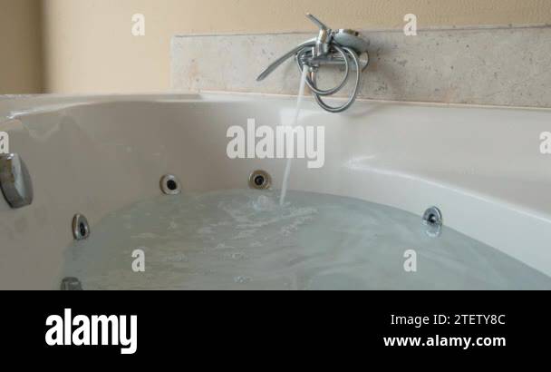 Jacuzzi filling with water. Water flows from the tap, the bathroom is ...