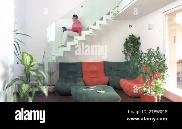 Single adult man indoor at home sitting on the staircase using ...