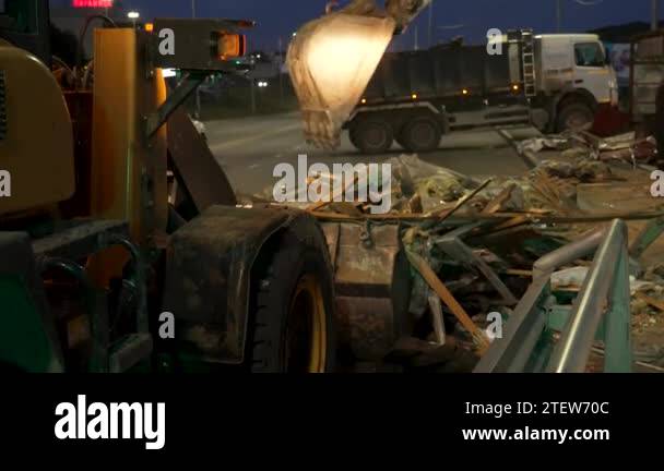 Yellow Front loader and excavator remove construction debris from a ...