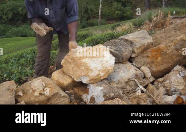 Close up of adult human hitting stone with sledgehammer for ...