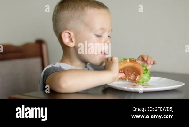 Little boy in fast food cafe eats burger. little kid eating burger ...