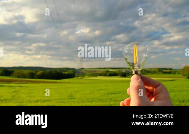 Electricity and green energy.Light bulb in hand on Pylon of the ...