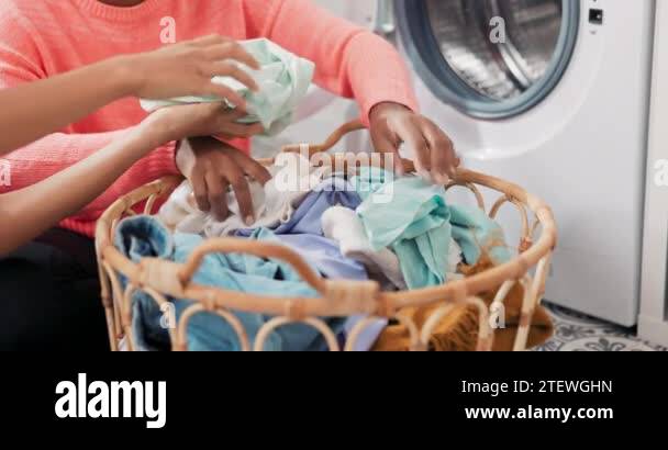 Close-up of a womans hands sitting on the laundry room floor, sorting ...