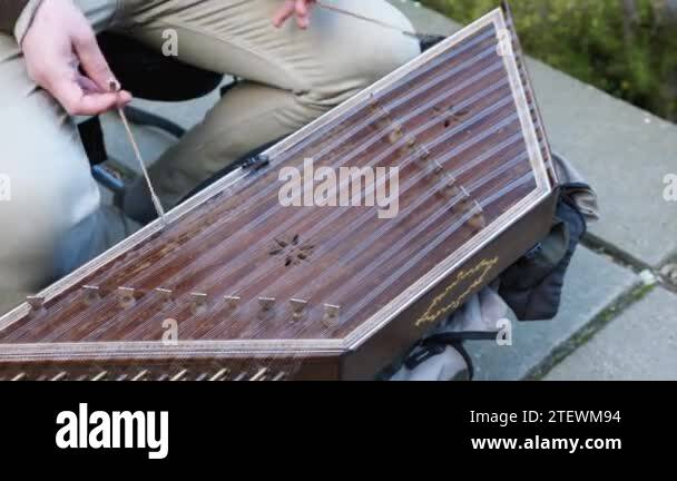 A musician plays a wooden string musical instrument by hitting it with ...