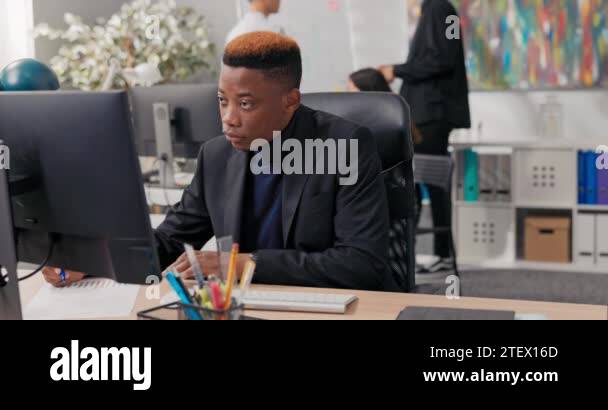Elegant man working in an office boy is sitting behind desk in front of ...