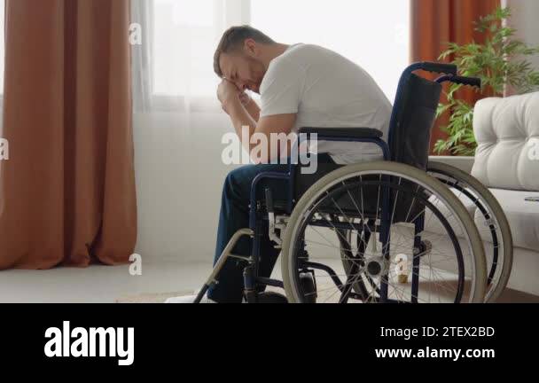 Sad disabled man sits in a wheelchair and cries in despair. Disability ...
