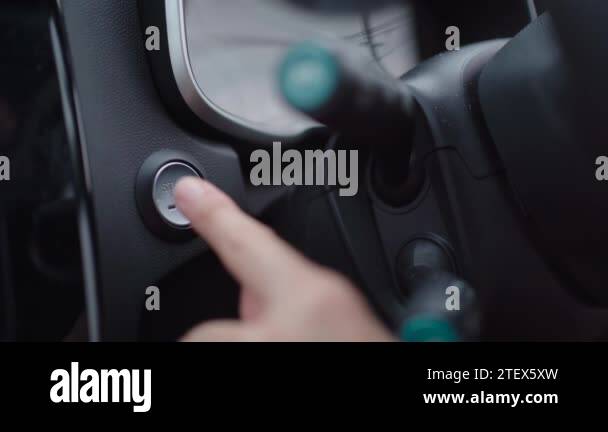 Driver pushing a vehicle engine start button, a modern car with keyless ...