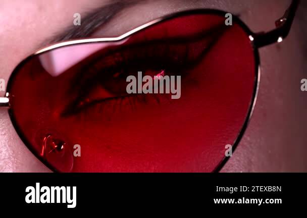 Female eye with fancy arrow make-up under heart-shaped red sunglasses ...