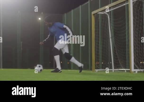 Wide tracking of fit young Black male athlete doing tricks with soccer ...