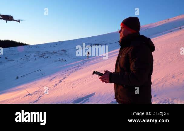Drone operator working on the hill covered with snow. A man that ...