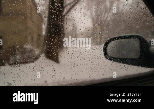 snow melts on glass. snowflakes on the glass of a car. raindrops behind ...