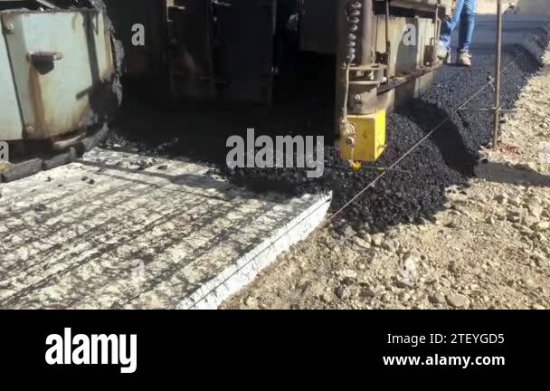 Asphalt paver lays asphalt mix on concrete foundation. Black top paver ...