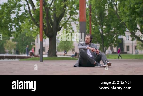 Young man, with mustaches and a beard, who sits on the wooden floor in ...