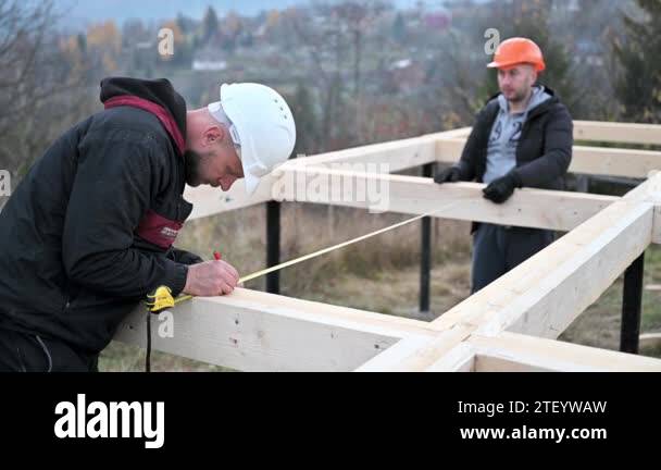 Men workers building wooden frame house on pile foundation. Carpenters ...