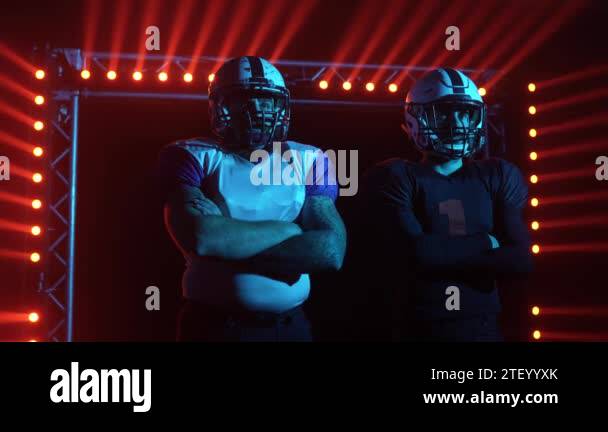Two confident professional quarterbacks stand on the field against a ...