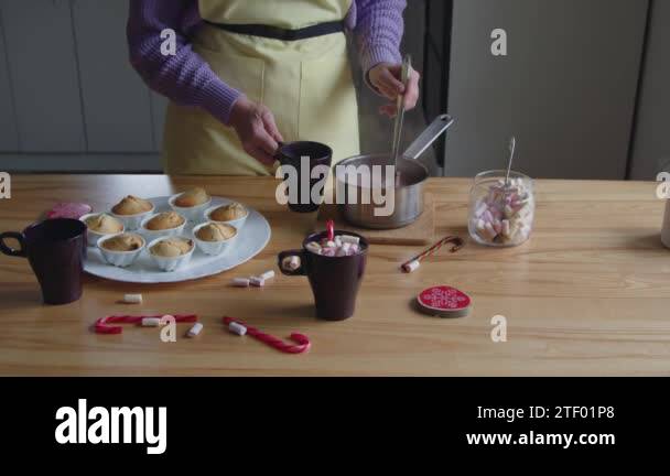 Woman is cooking sweet snack at home, hot chocolate drink and muffins ...