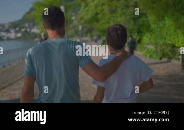 Father and son walking together outside dad putting arm around child ...